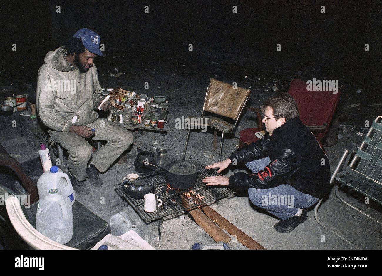 Artist Chris Pape, right, keeps warm last February by the cooking fire ...