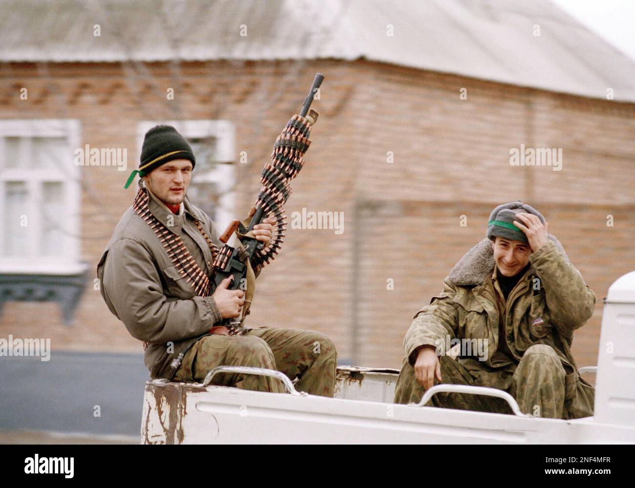 Two Chechen separatist fighters, one holding a machine gun, ride in the ...