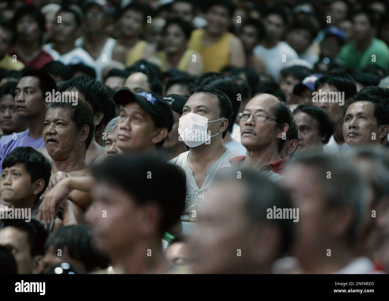 A Filipino uses a mask as he watches a free live satellite broadcast of ...