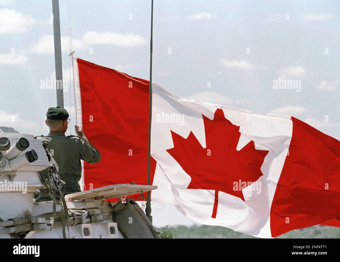 A Canadian soldier atop an armored personel carrier lowers the Canadian ...