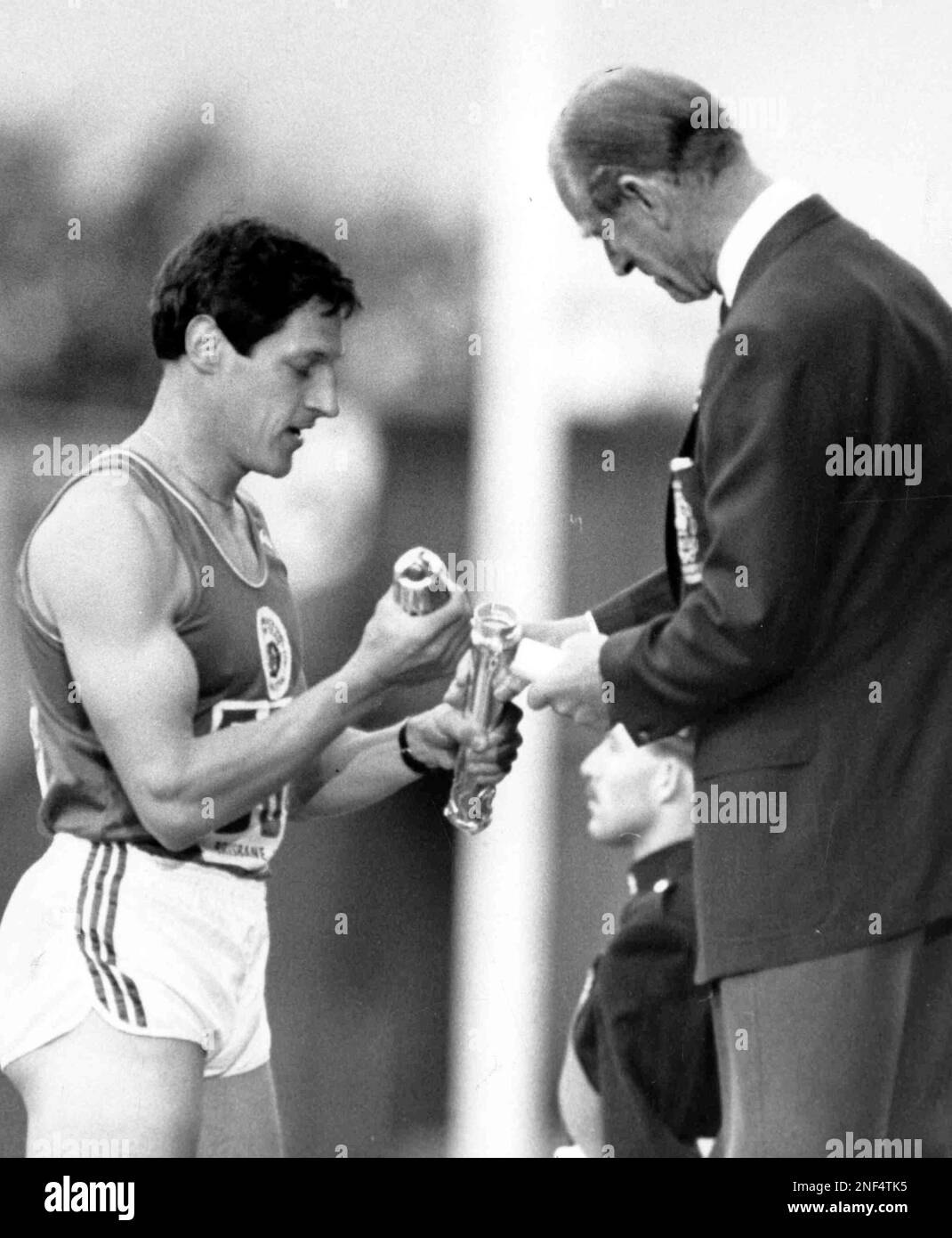 Scotland's Allan Wells, left, holds the baton from which the Duke of ...