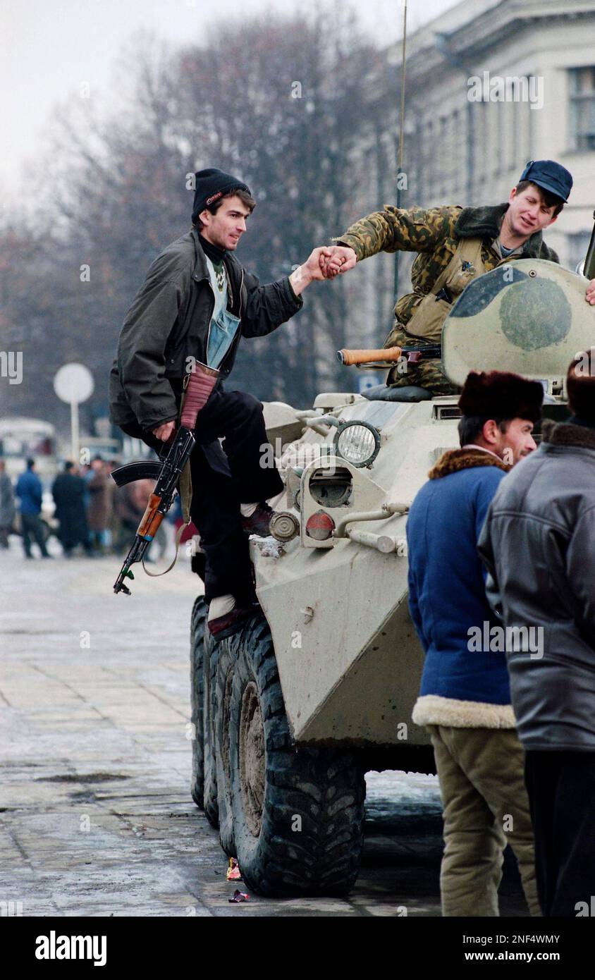 A Chechen soldier helps an armed volunteer to get aboard the APC ...