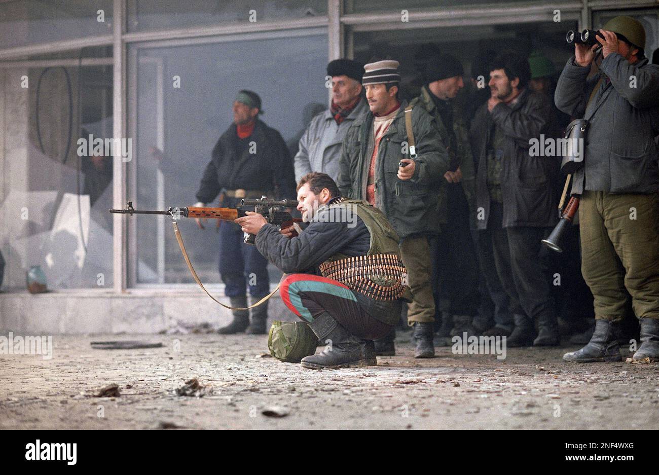As a comrade scans the distance with binoculars, a Chechen fighter ...