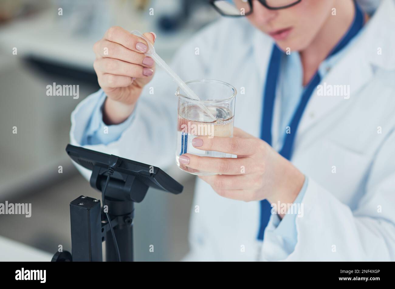 This is very interesting. a focused young female scientist mixing chemicals together at their ...