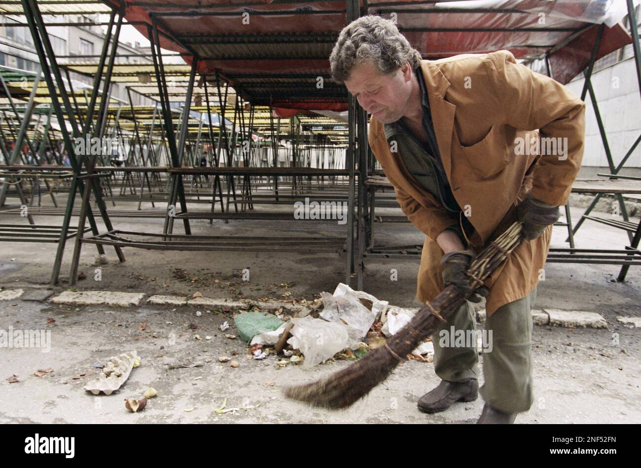 A street-sweeper puts his back into his work and cleans up the empty ...