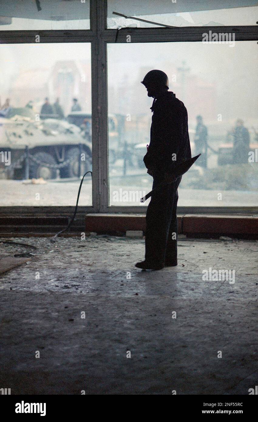 A Chechen fighter, holding a rocket propelled grenade, stands beside ...