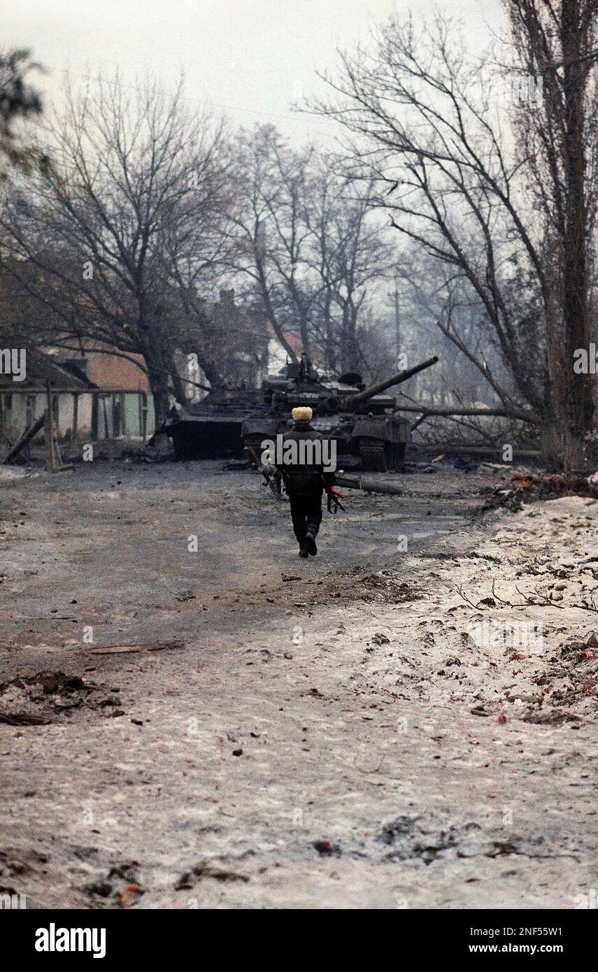 A Chechen fighter walks towards two destroyed Russian tanks put out of ...