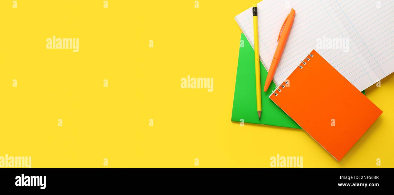 Notebooks, pen and pencil on yellow background with space for text ...