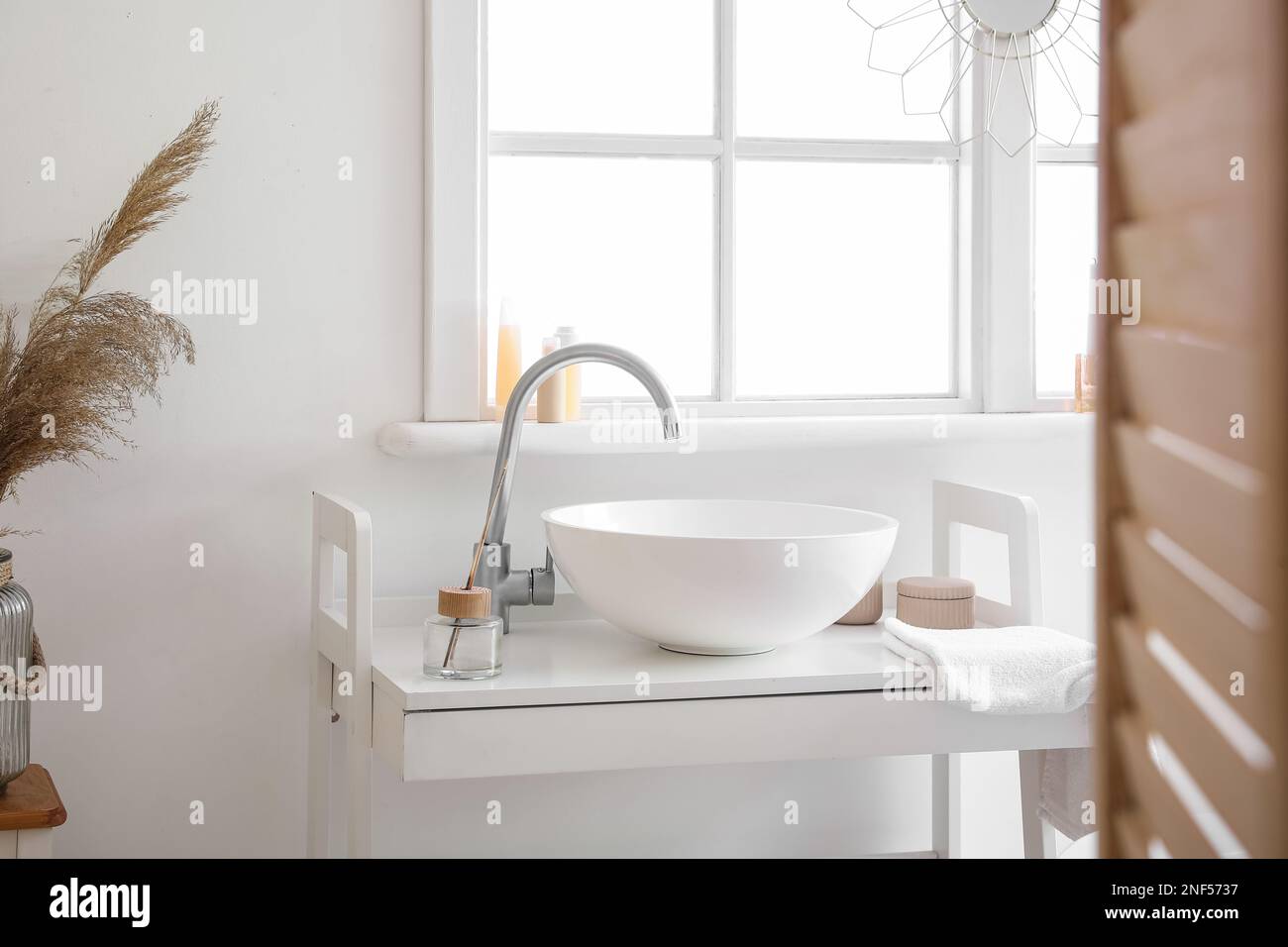 Interior of bathroom with ceramic sink and reed diffuser near window ...