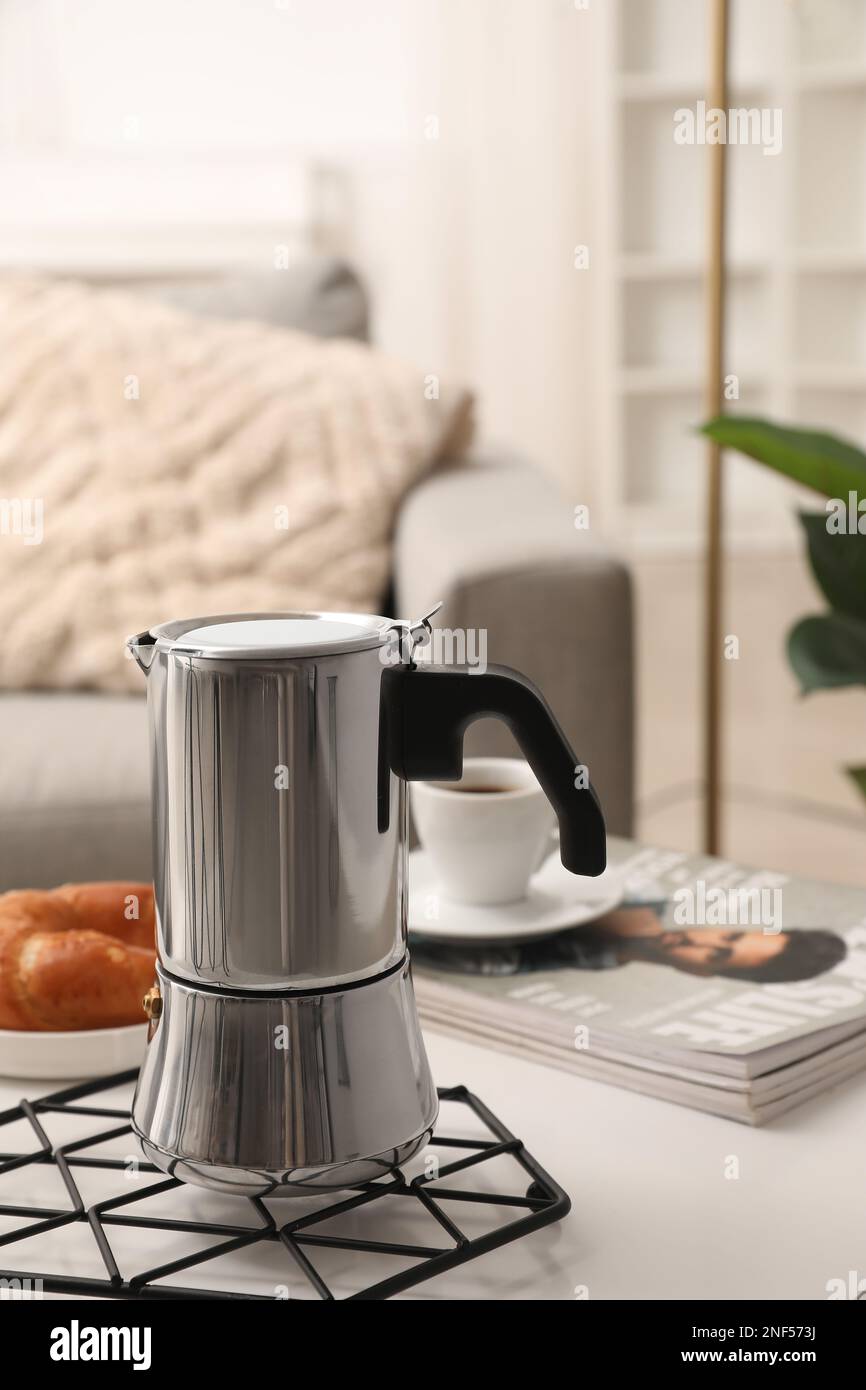 Grid with geyser coffee maker and delicious croissant on table in ...