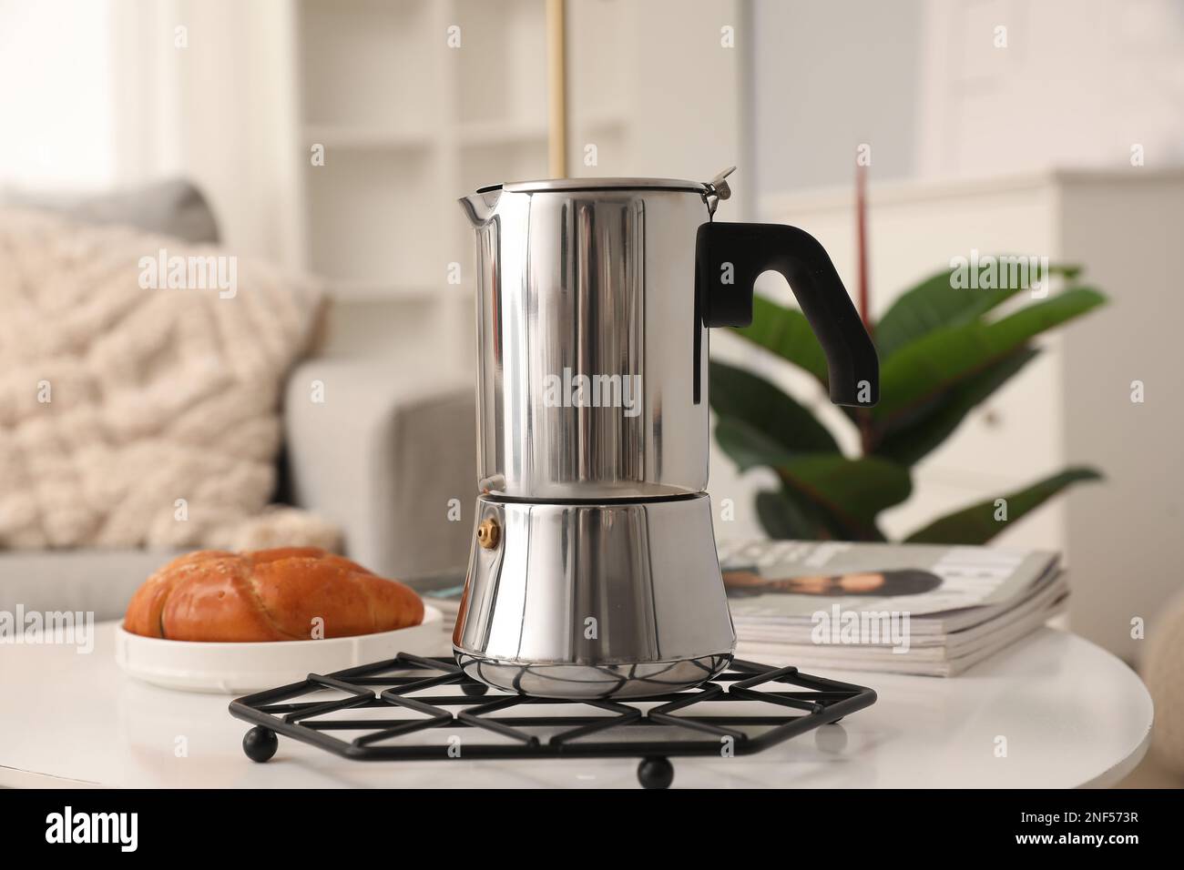 Grid with geyser coffee maker and delicious croissant on table in ...