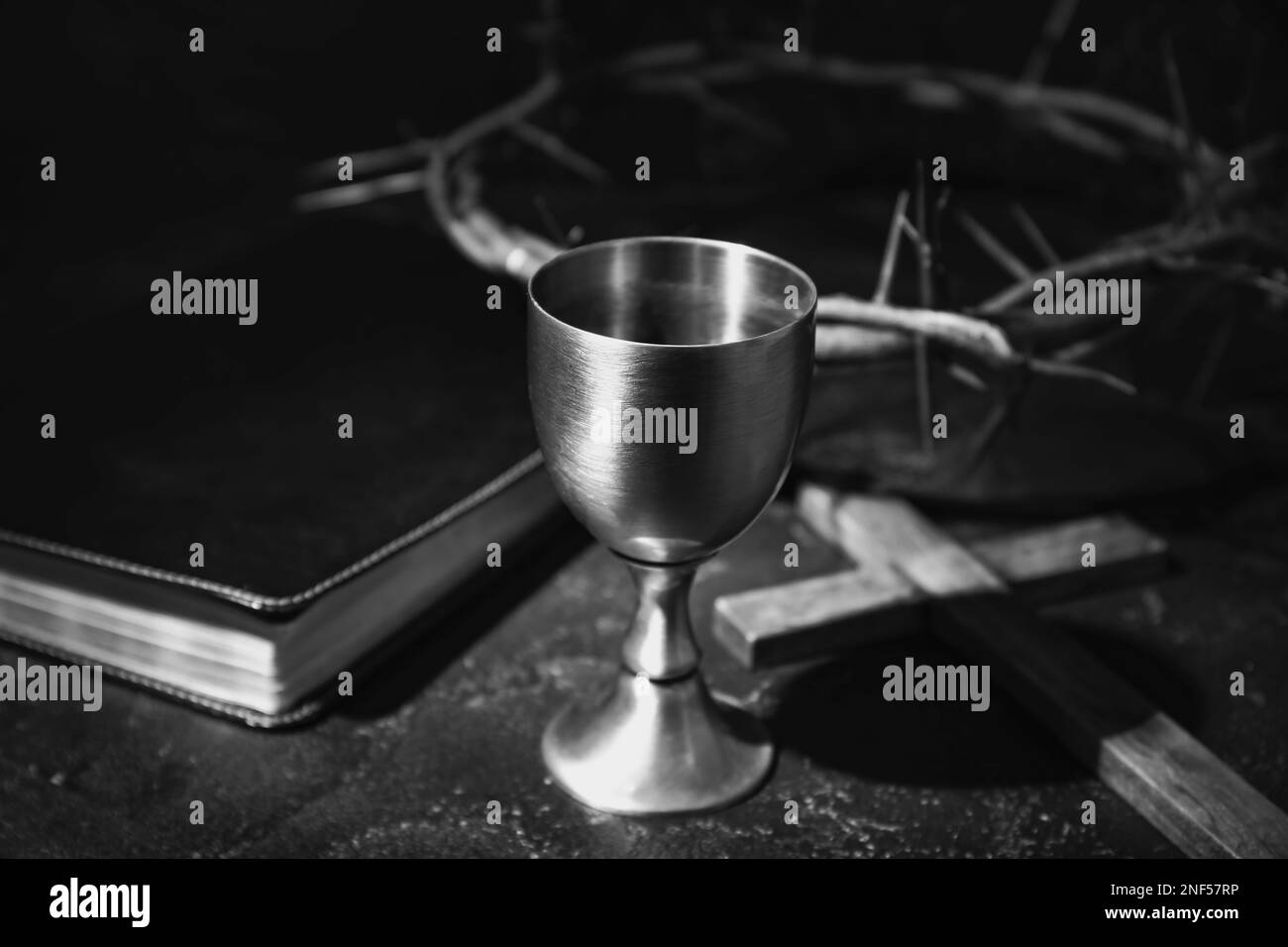 Wine cup, crown of thorns, cross and Holy Bible on dark background ...