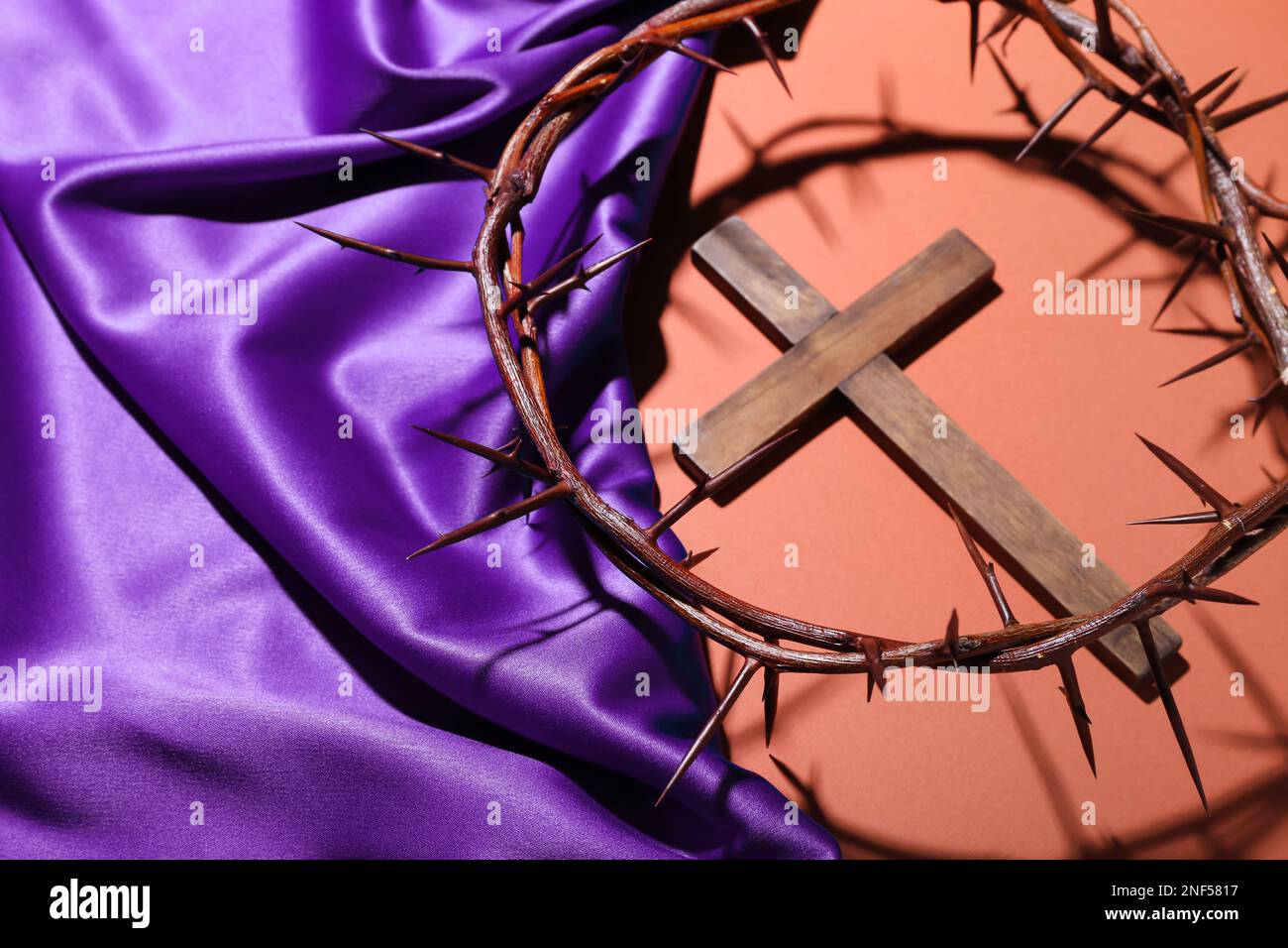 Cross with crown of thorns and purple fabric on red background. Good ...