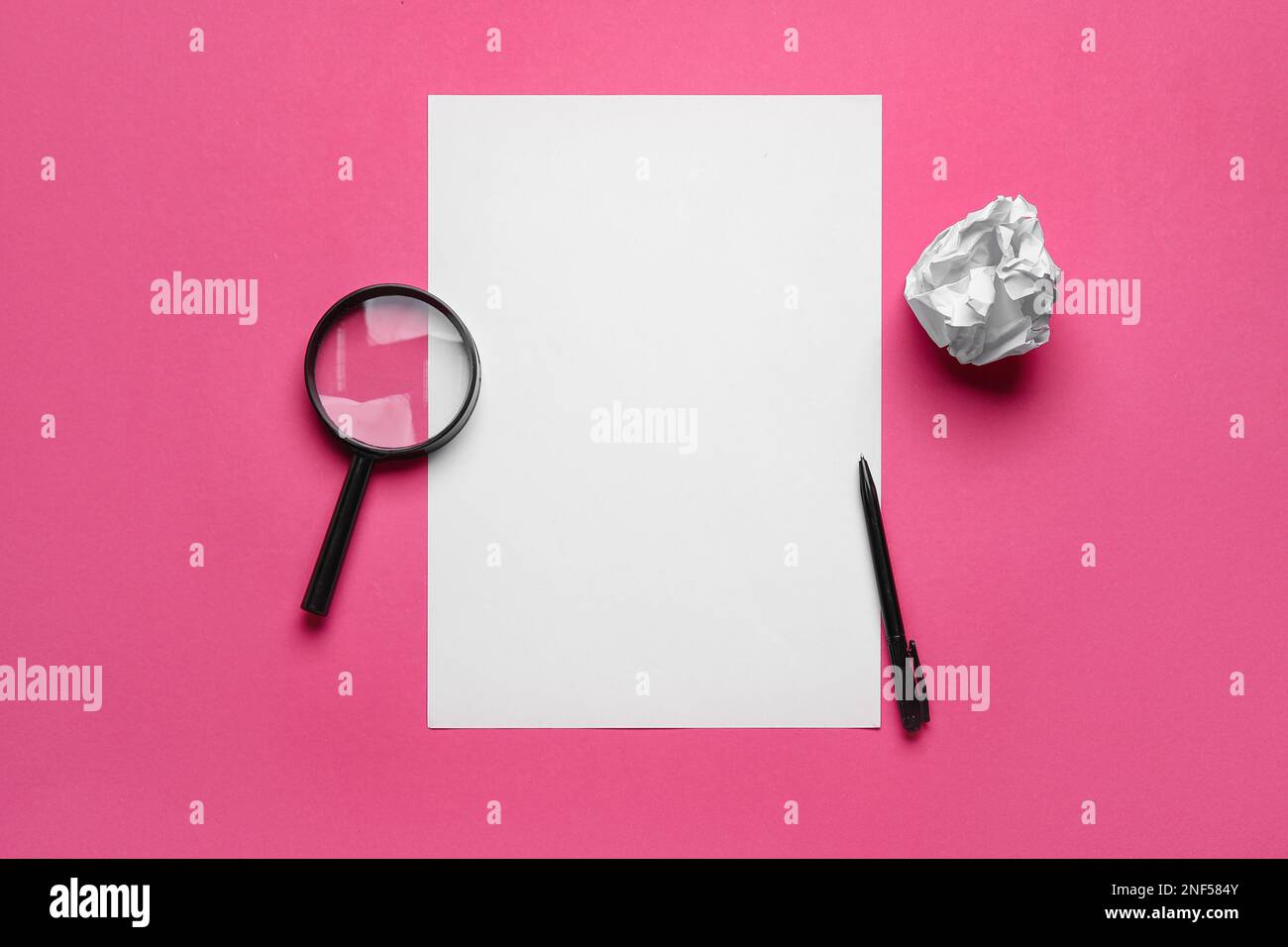 Blank sheet, crumpled paper ball, pen and magnifier on pink background ...