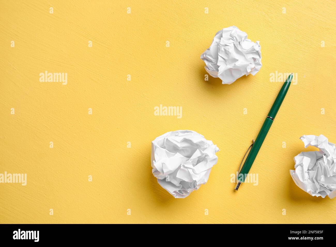 Crumpled paper balls and pen on yellow background. World Poetry Day ...