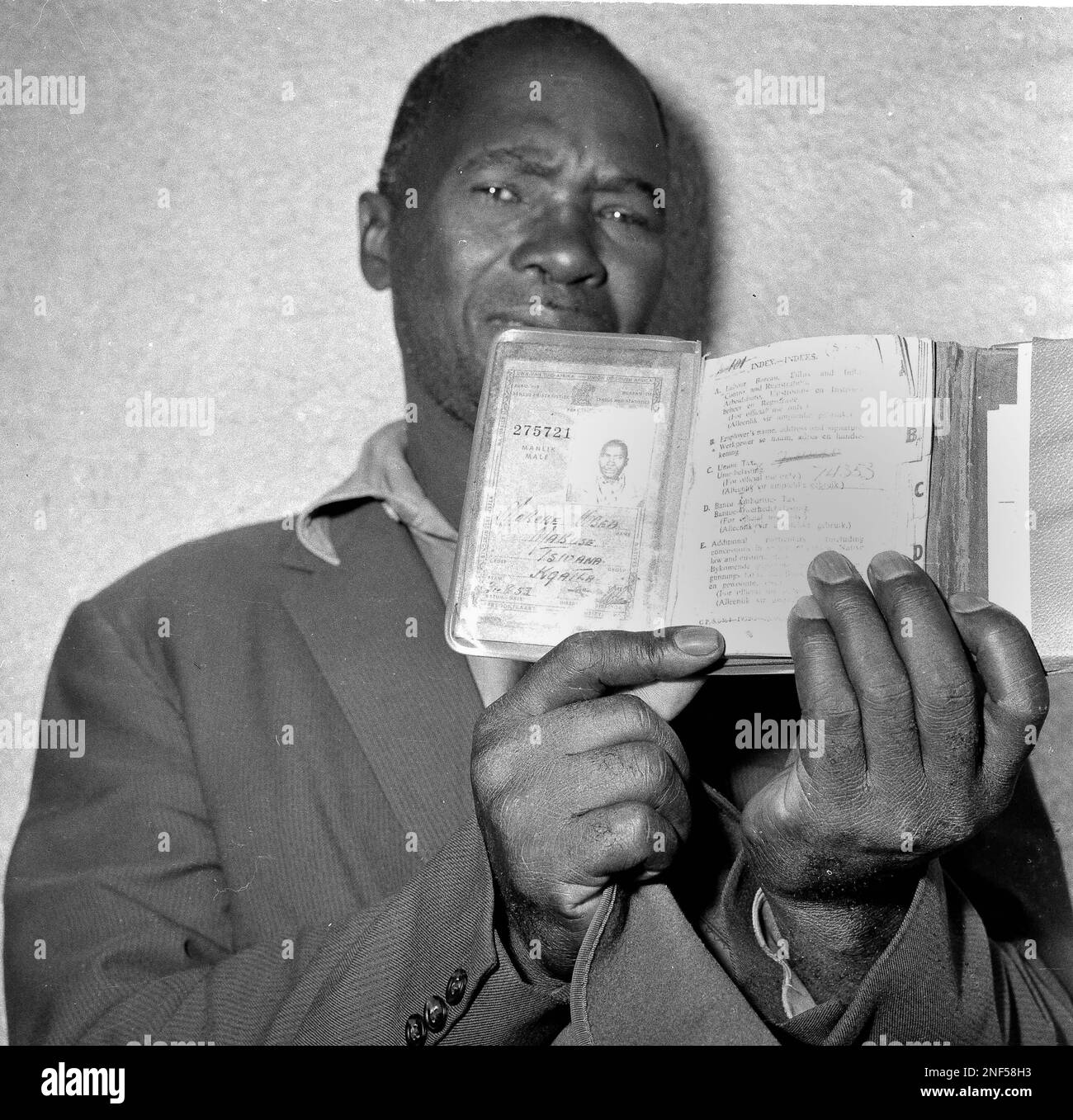 A South African man shows his pass for re-employment from the ...