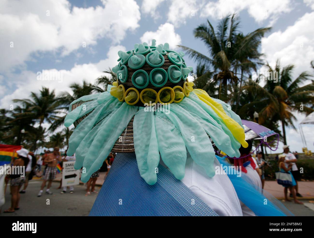 A woman wears a hat decorated with condoms as she marches with the ...