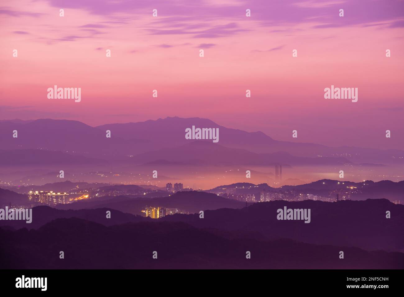 Clouds are among the mountains. There are tall buildings in the valley ...