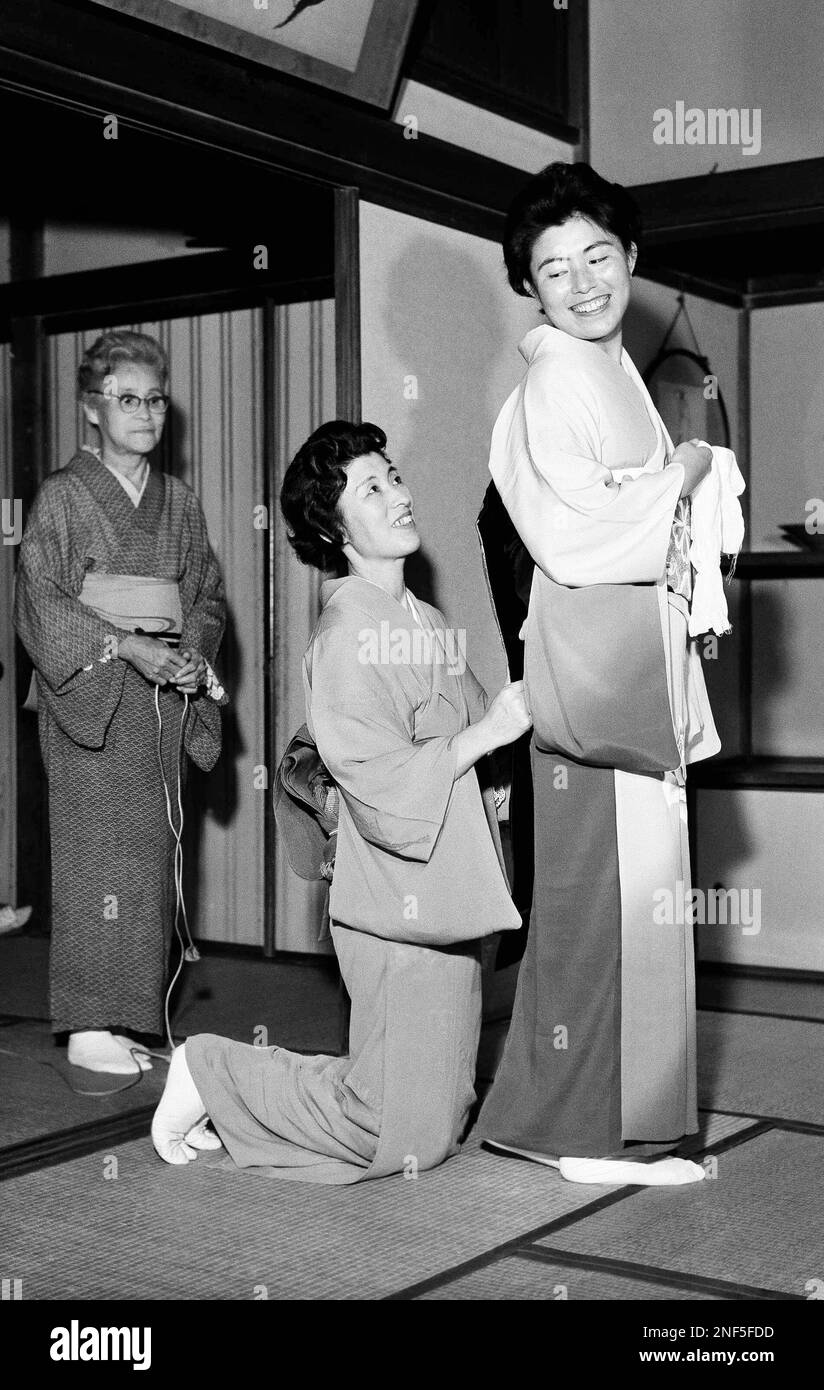 A modern Tokyo young woman, Akiko Yamamoto, right, gets into a traditional kimono with the help ...