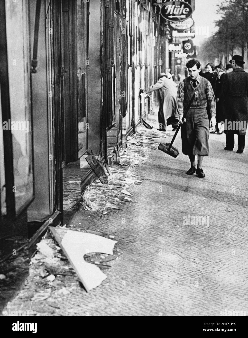 A young man with a broom clears broken glass from shop windows in ...