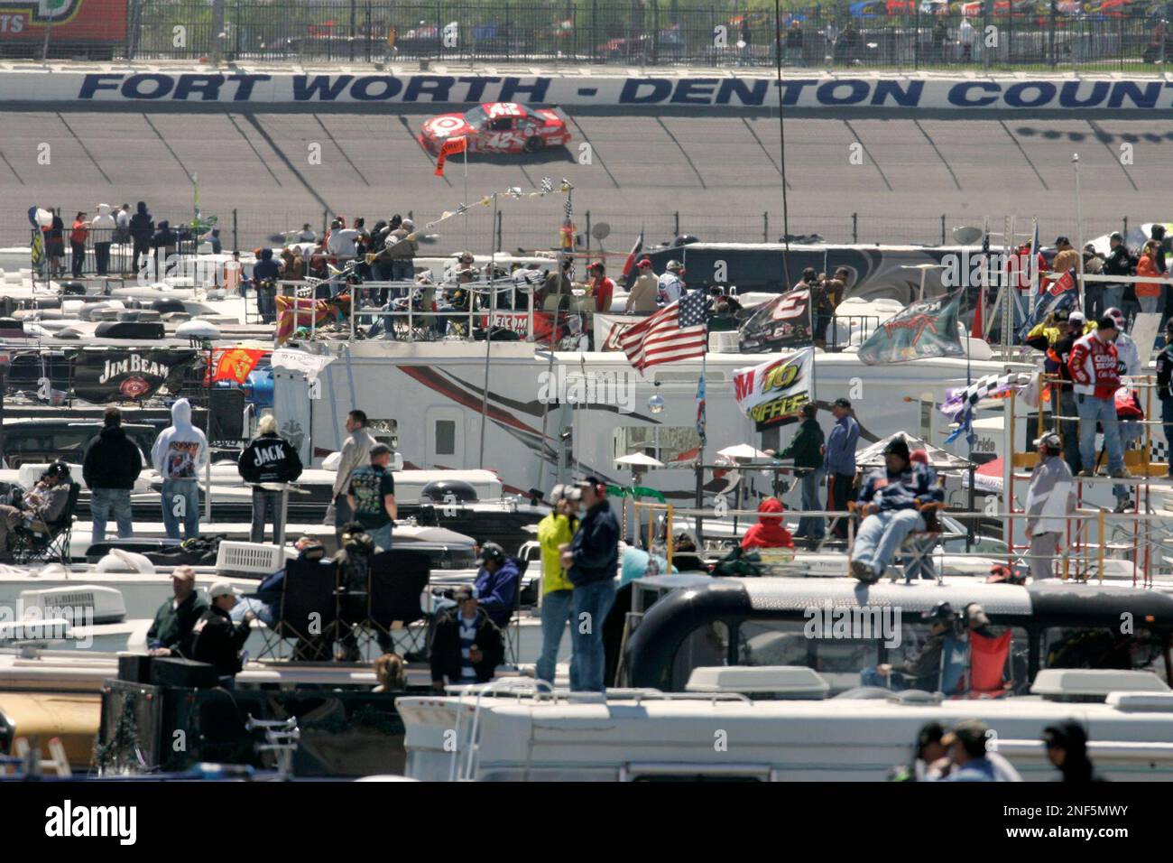 Racing fans stand atop scaffolding and their vehicles in the infield ...