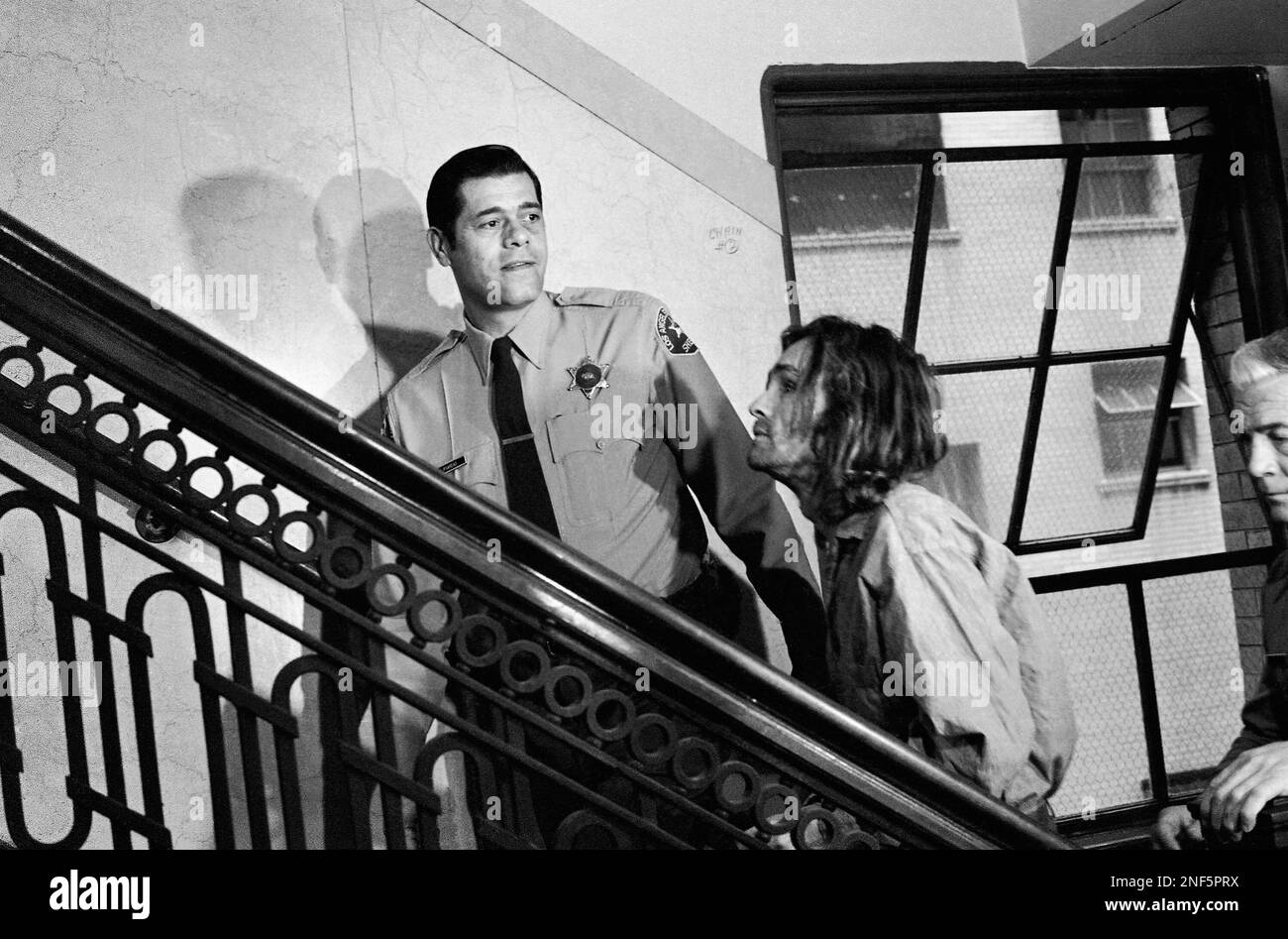 Hippie cult "family" leader Charles M. Manson is led up a stairway back ...