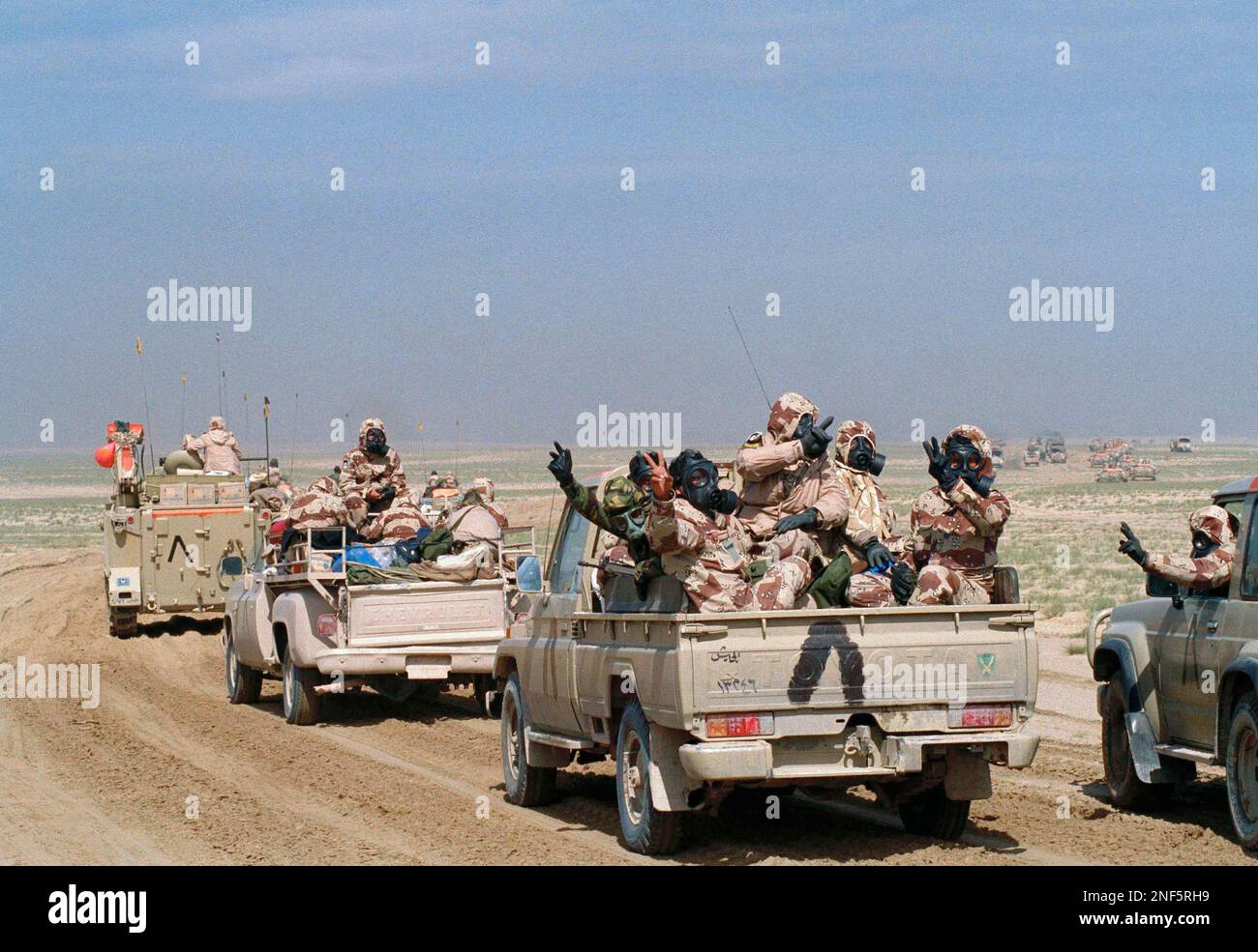 Kuwaiti troops wearing gas masks and protective suits as they roll ...