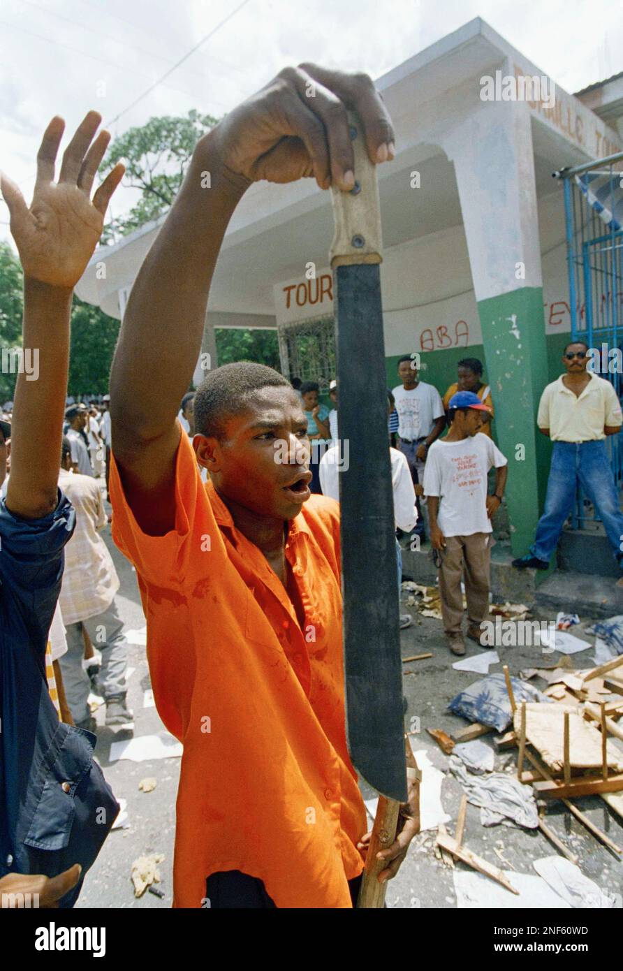 A young man holds up a machete taken from the headquarters of FRAPH on ...