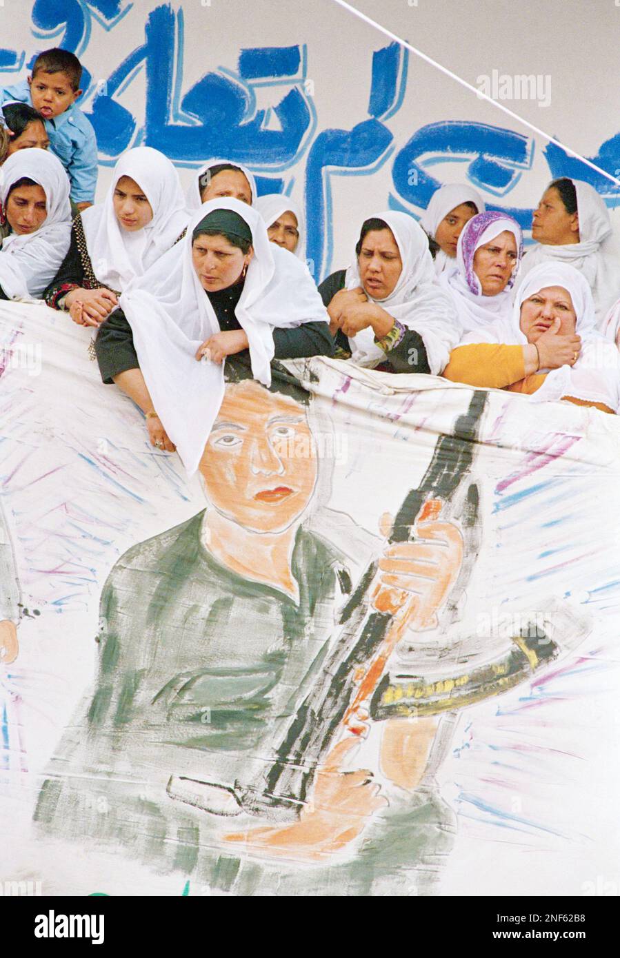 Palestinian women lean over a banner as they watch a huge PLO-sponsored ...