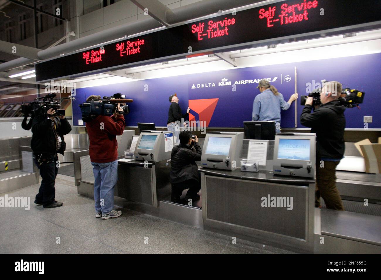 Members of the media surround the placement of a new Delta sign to the ...