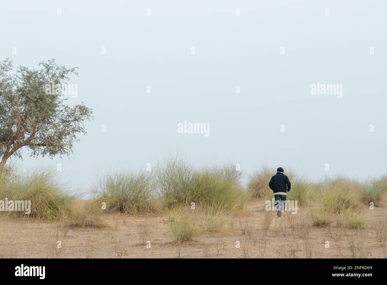 A person running on a dry field with grass clumps around Stock Photo ...