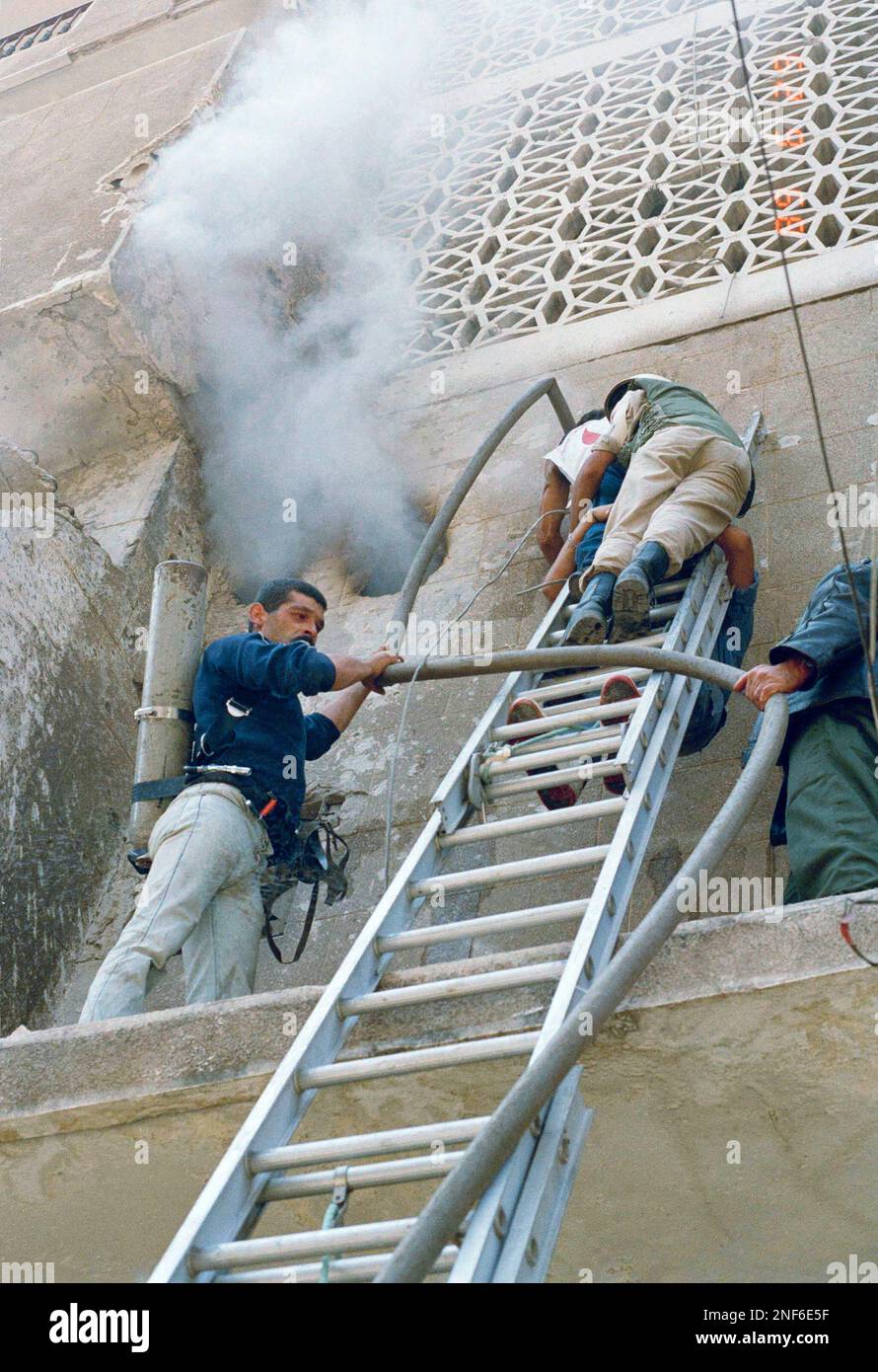 Fireman helped by a civil defense worker, as he tries to extinguish a ...