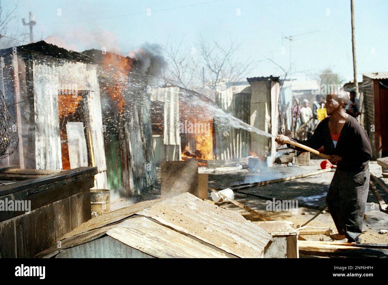An old man tries to extinguish his shack which was set alight during ...