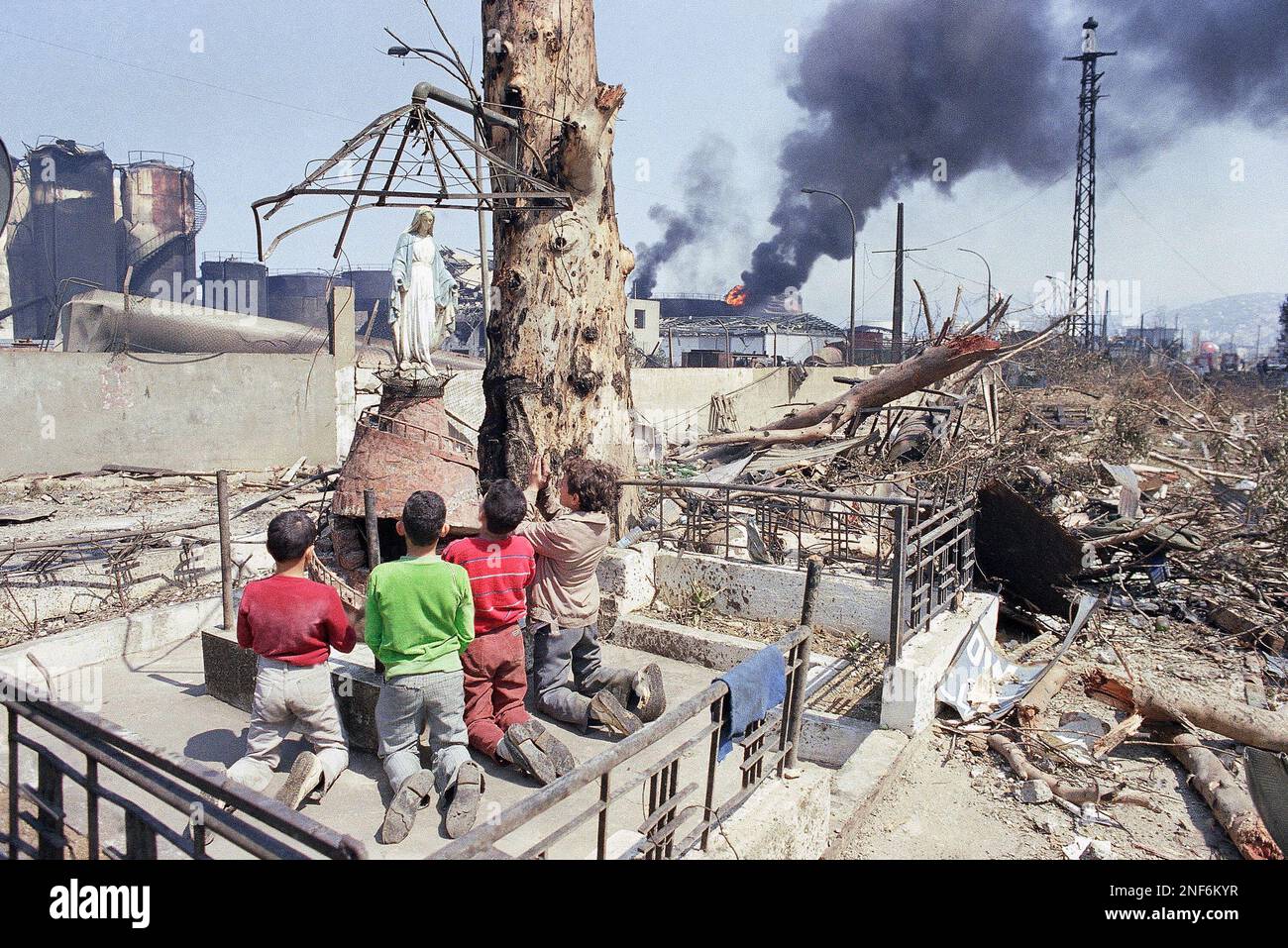Christian children kneel amongst the debris of an exploded fuel tank in ...