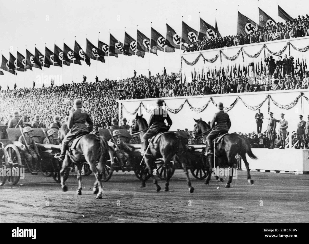 Mounted gun crews pass German Chancellor Adolf Hitler, saluting right ...