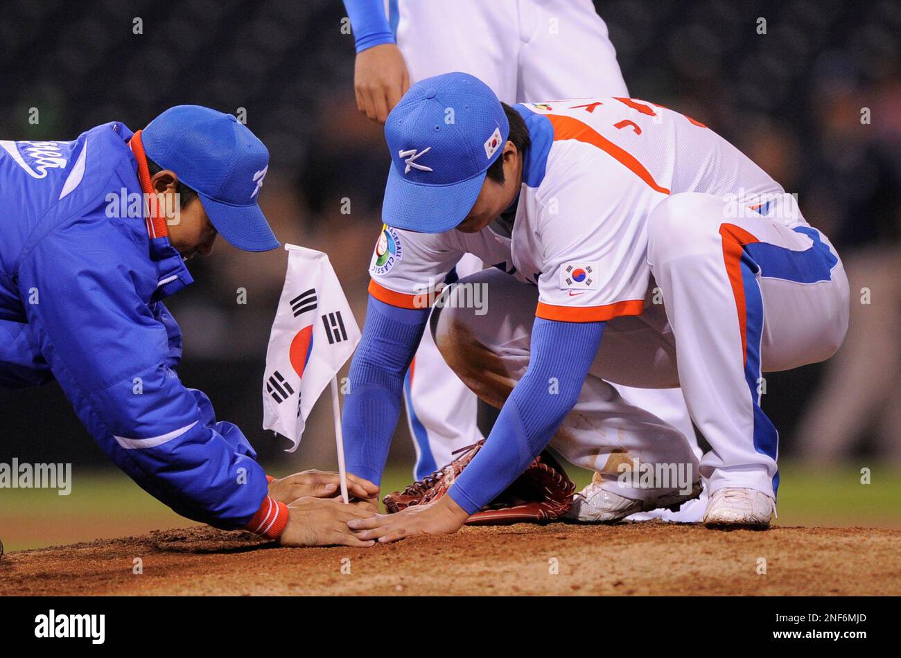South Korea's Bong Jung Keun, left, and Lee Jin Young plant a Korean flag on the pitcher's mound ...