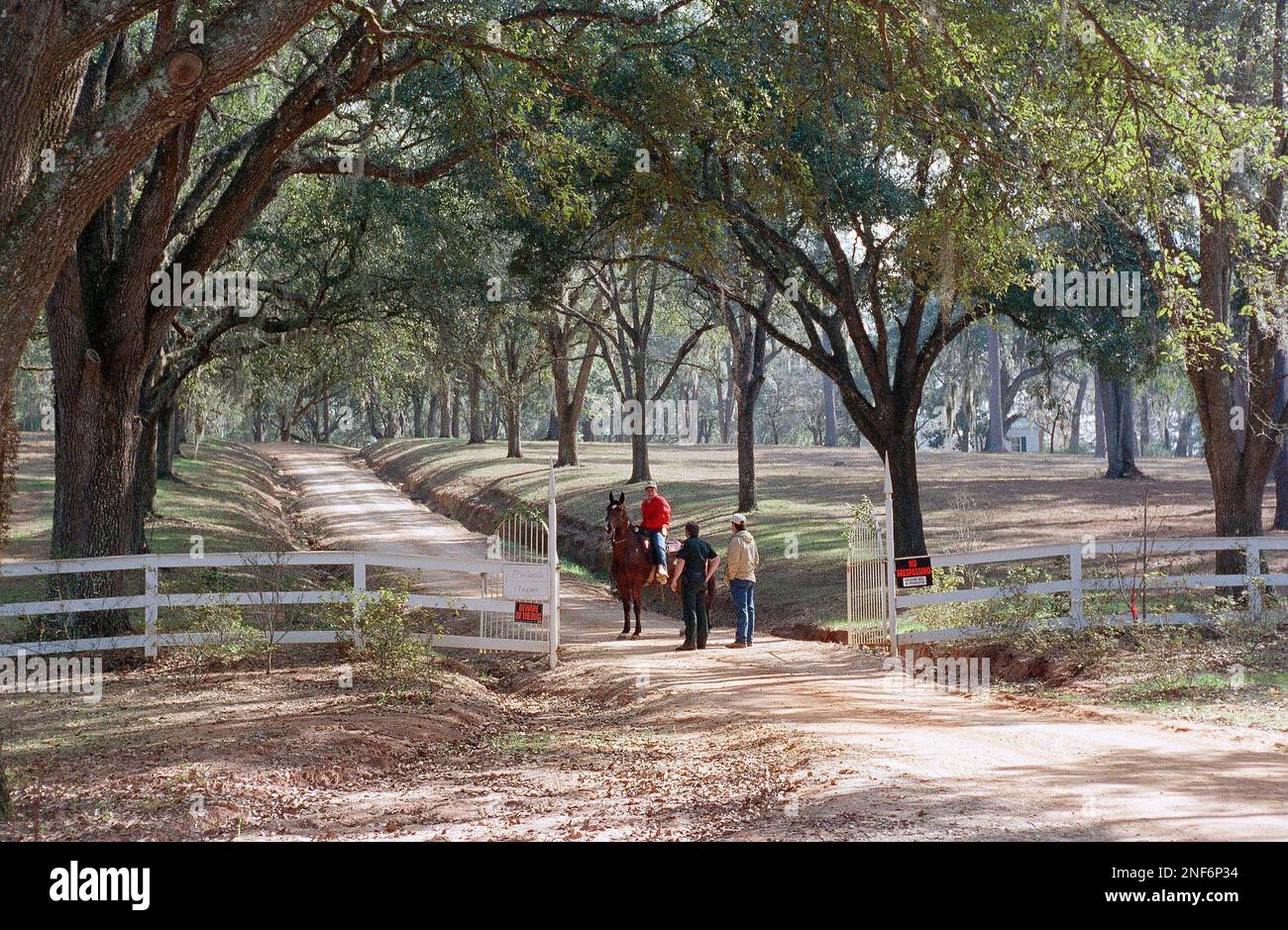 Security personnel, both on foot and horse, guard the oak canopy entrance drive and main gate in ...