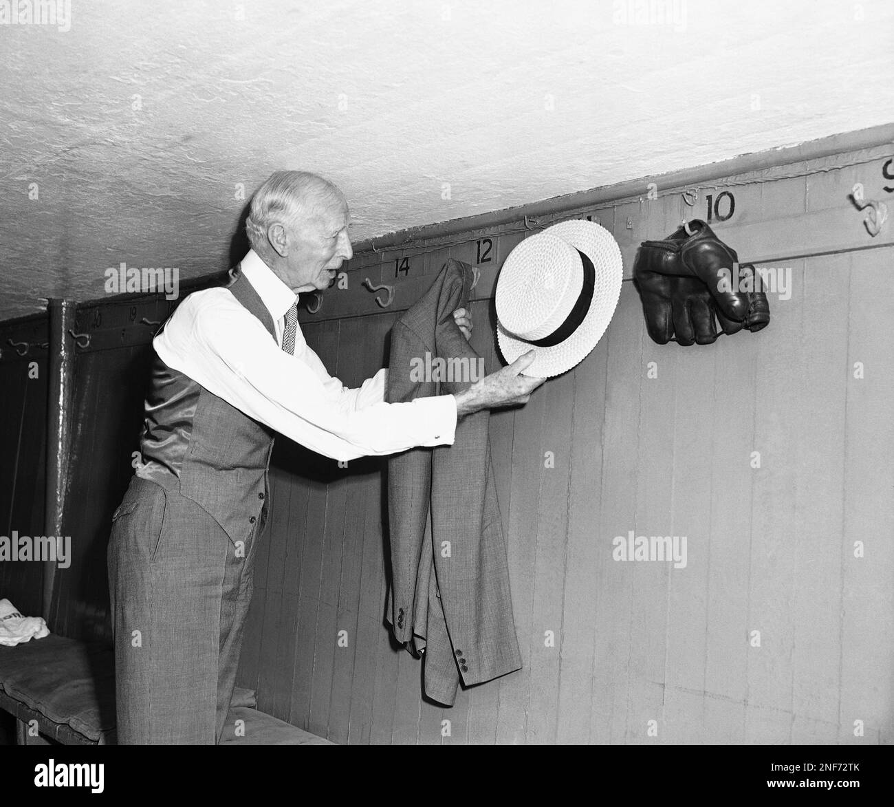 Connie Mack hangs up his hat and coat in the dugout at Yankee Stadium ...