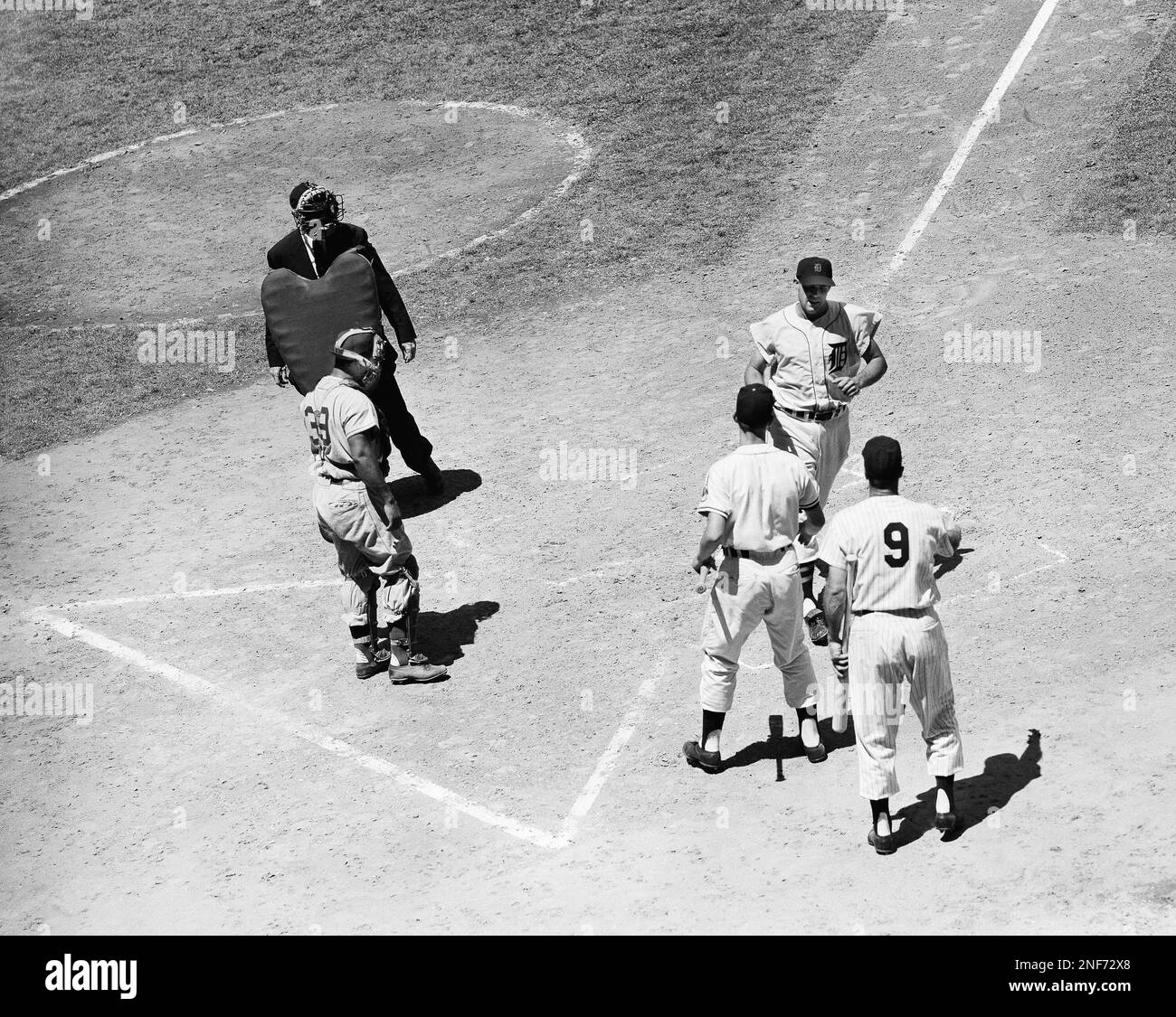 Ray Boone of the Detroit Tigers is greeted at home plate by batboy and ...