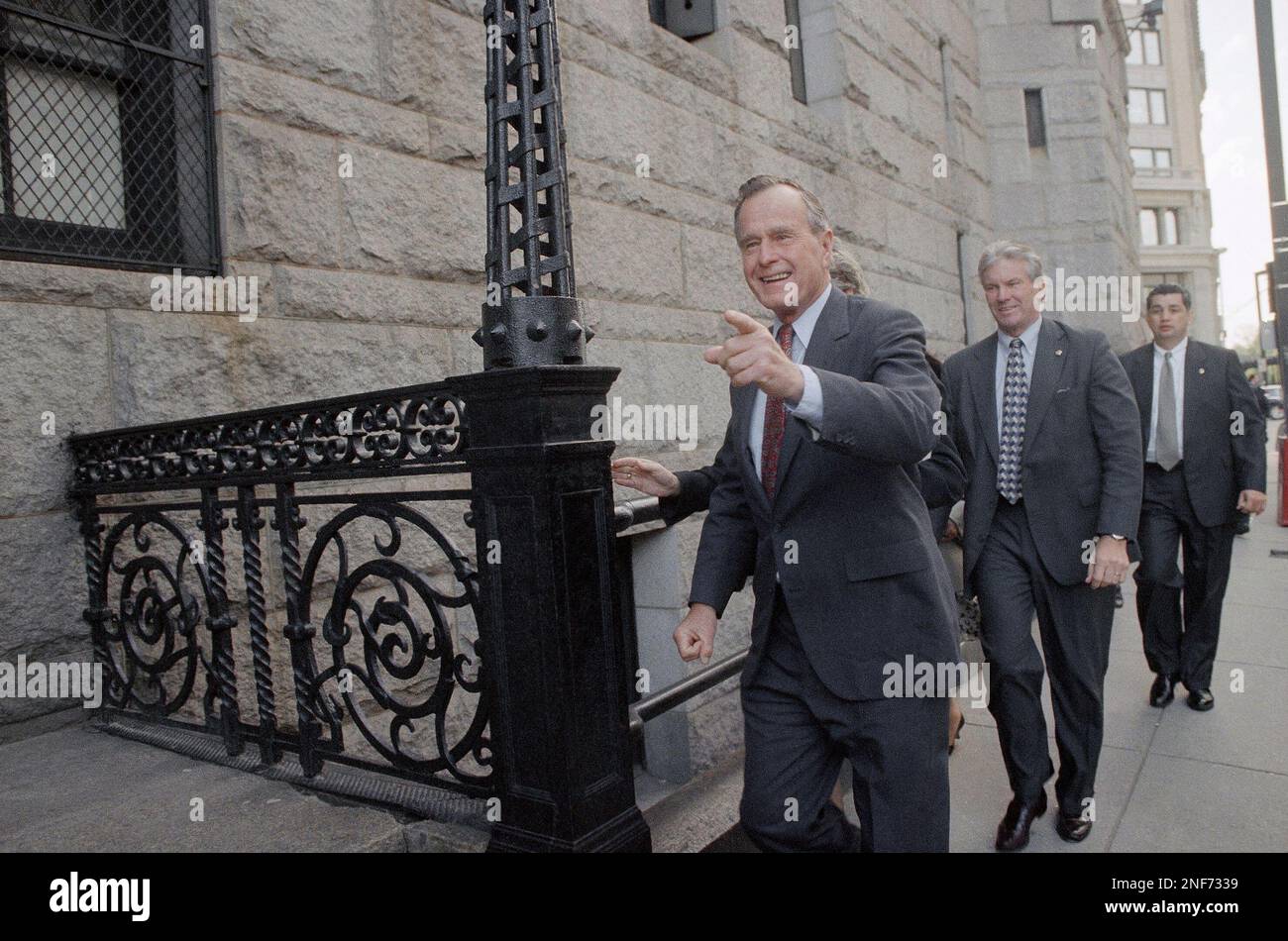 Former U.S. President George H. Bush points as he quickly walks past ...
