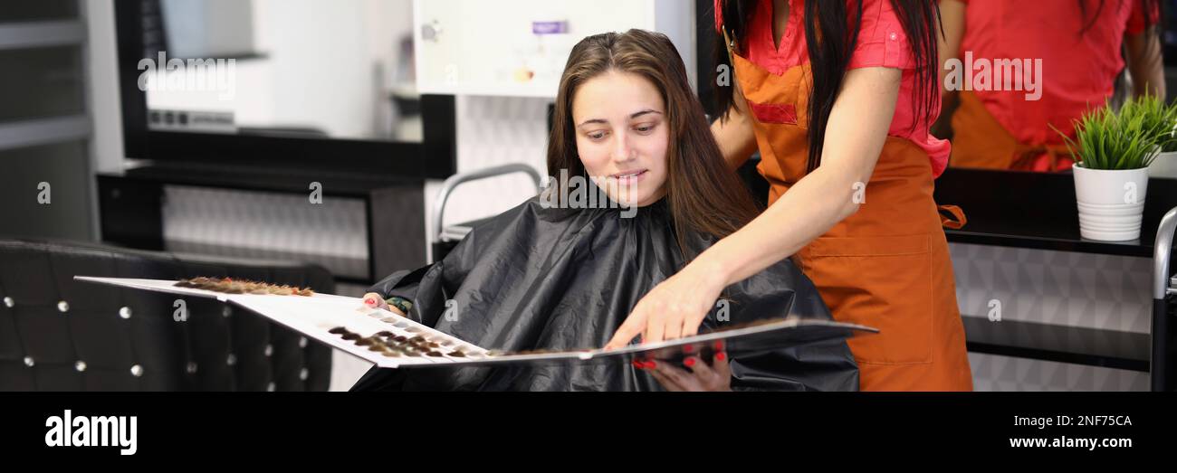 Professional female hairdresser and client choose hair dye color from ...