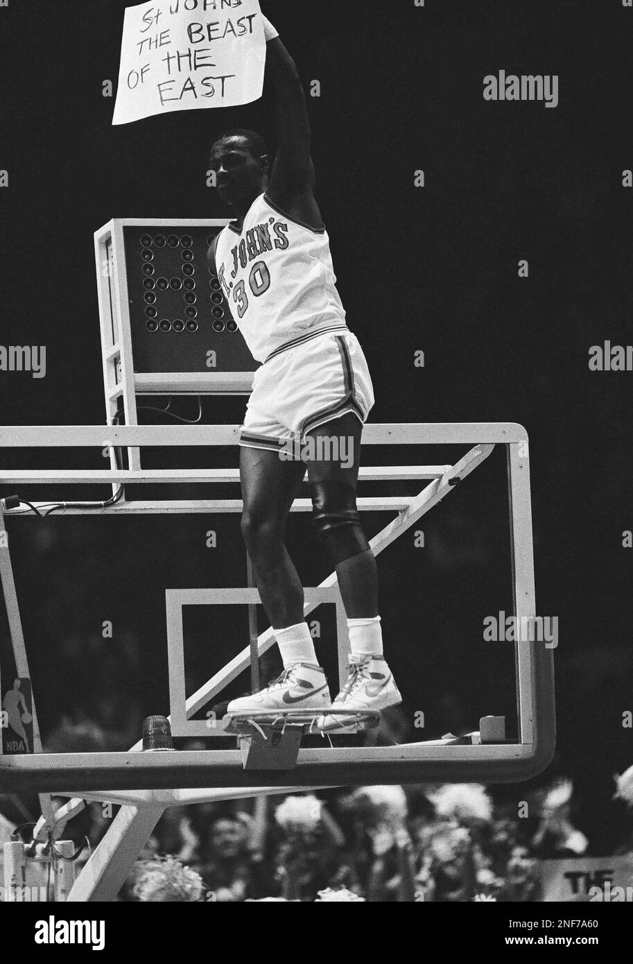 St. John’s forward Willie Glass holds a sign high above the rim in ...