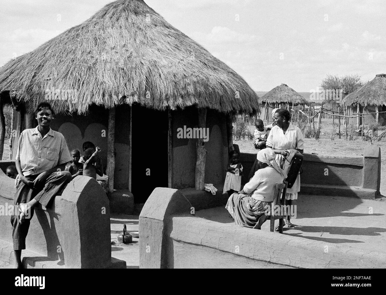 Residents of a Bechuanaland village at mud huts and straw roofs in ...
