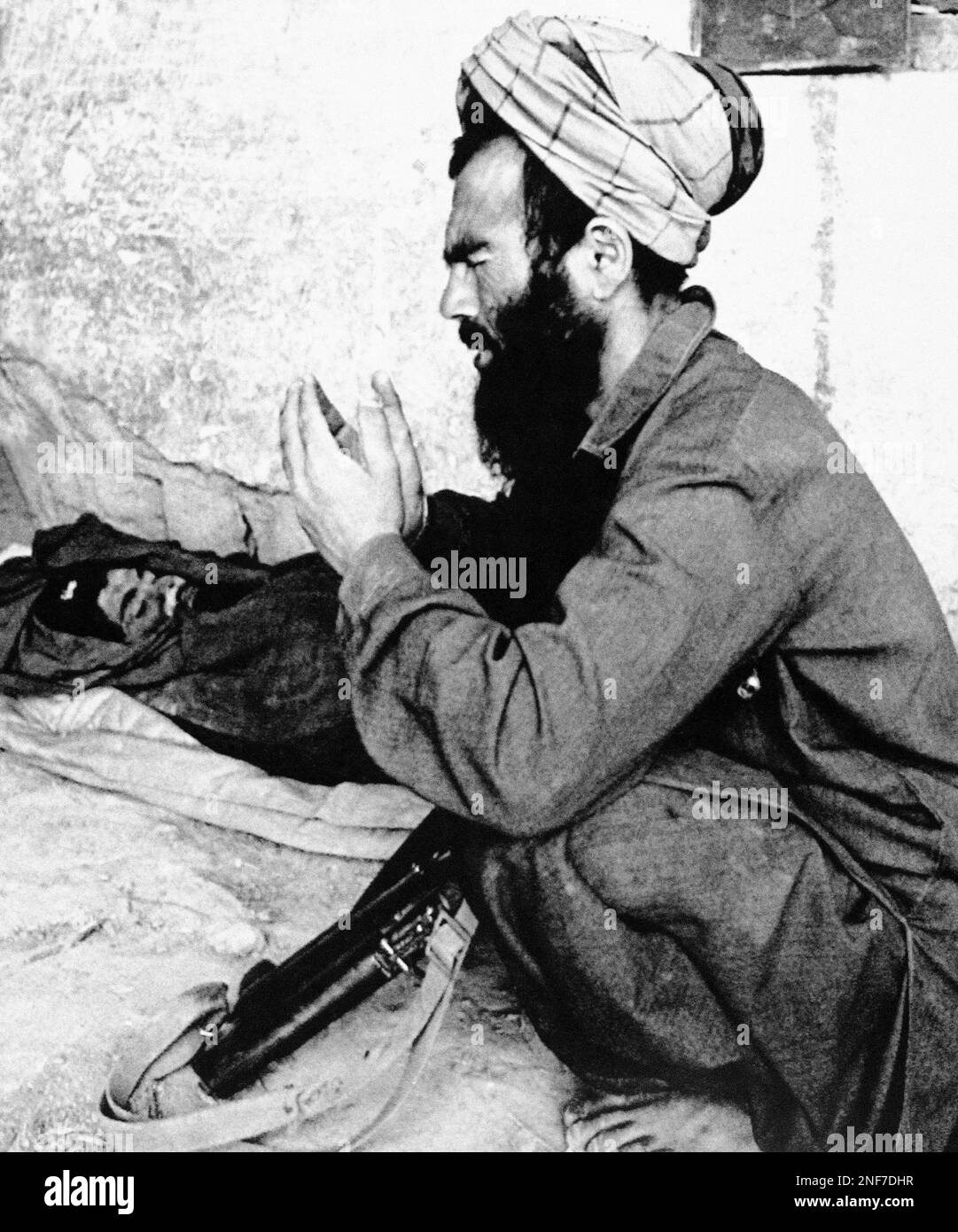 An Afghan rebel prays for his fallen fellow who was killed by a bomb ...