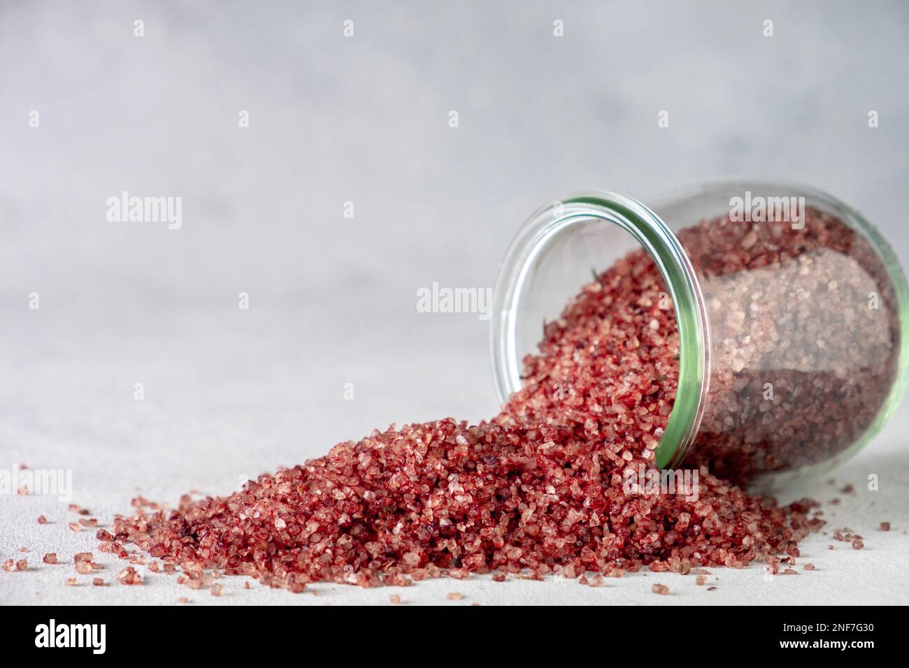 Red wine flavored salt spills out of a glass jar. Gourmet condiment to ...