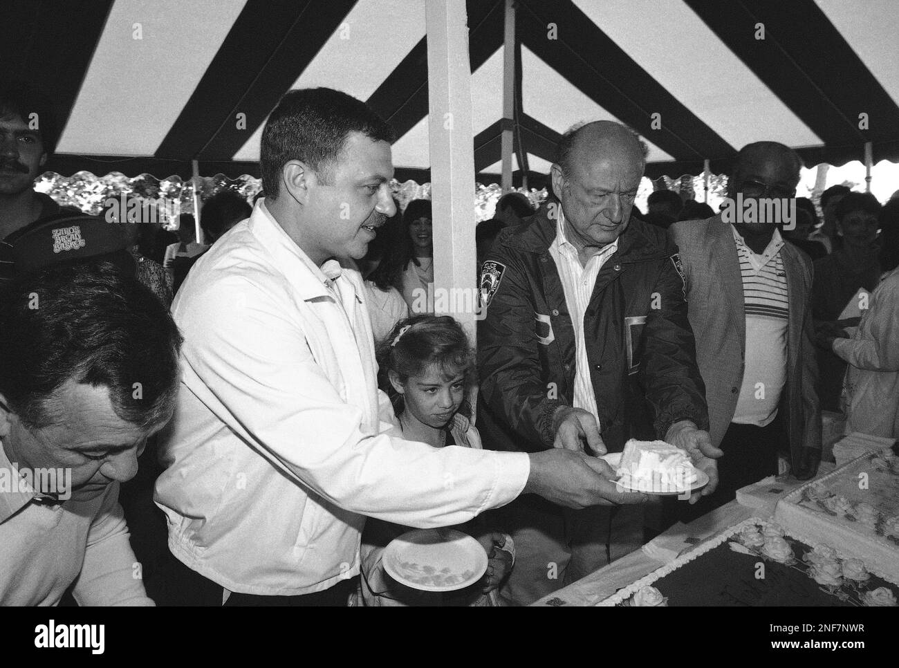 New York's Mayor Ed Koch, right, helps pass out cake at a party he is ...