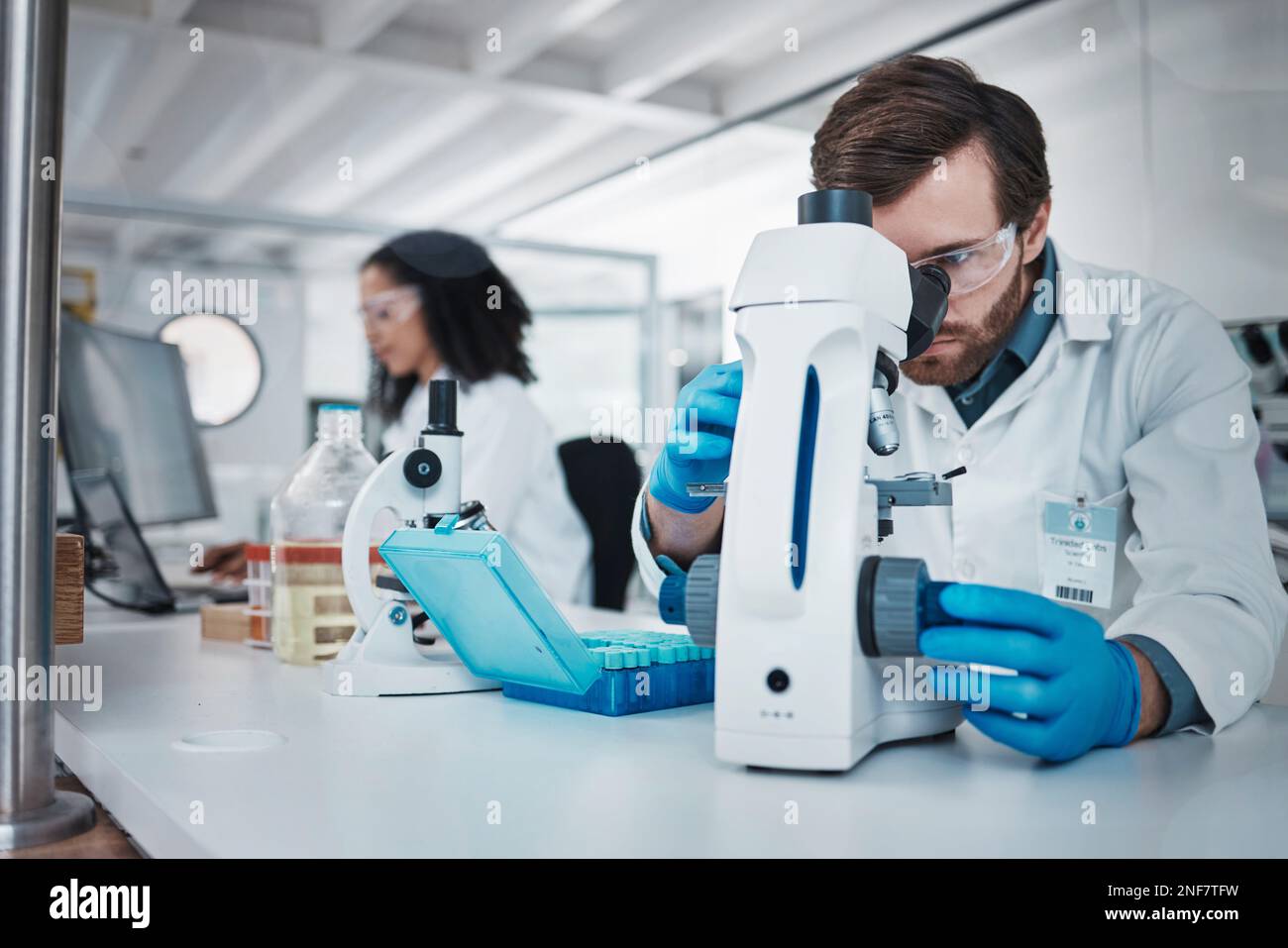 Man, doctor and forensic scientist with microscope for examination ...