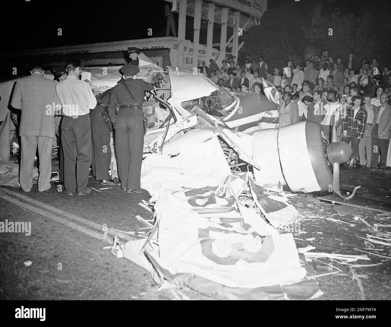 Spectators crowd around the wreckage of a twin-engine plane which ...