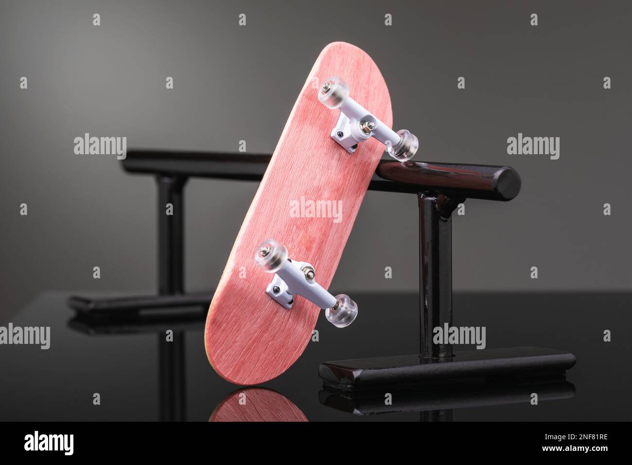 Pink color fingerboard with white chassis on black metal railings on a ...