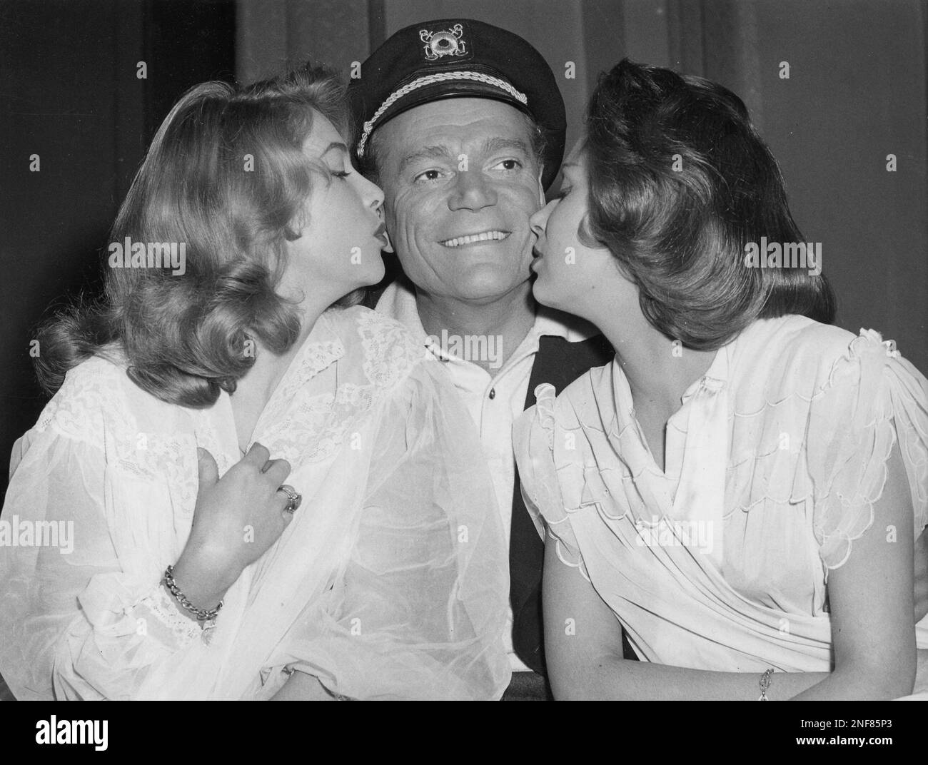 U.S. American actor and singer Eddie Constantine, is kissed by the two ...